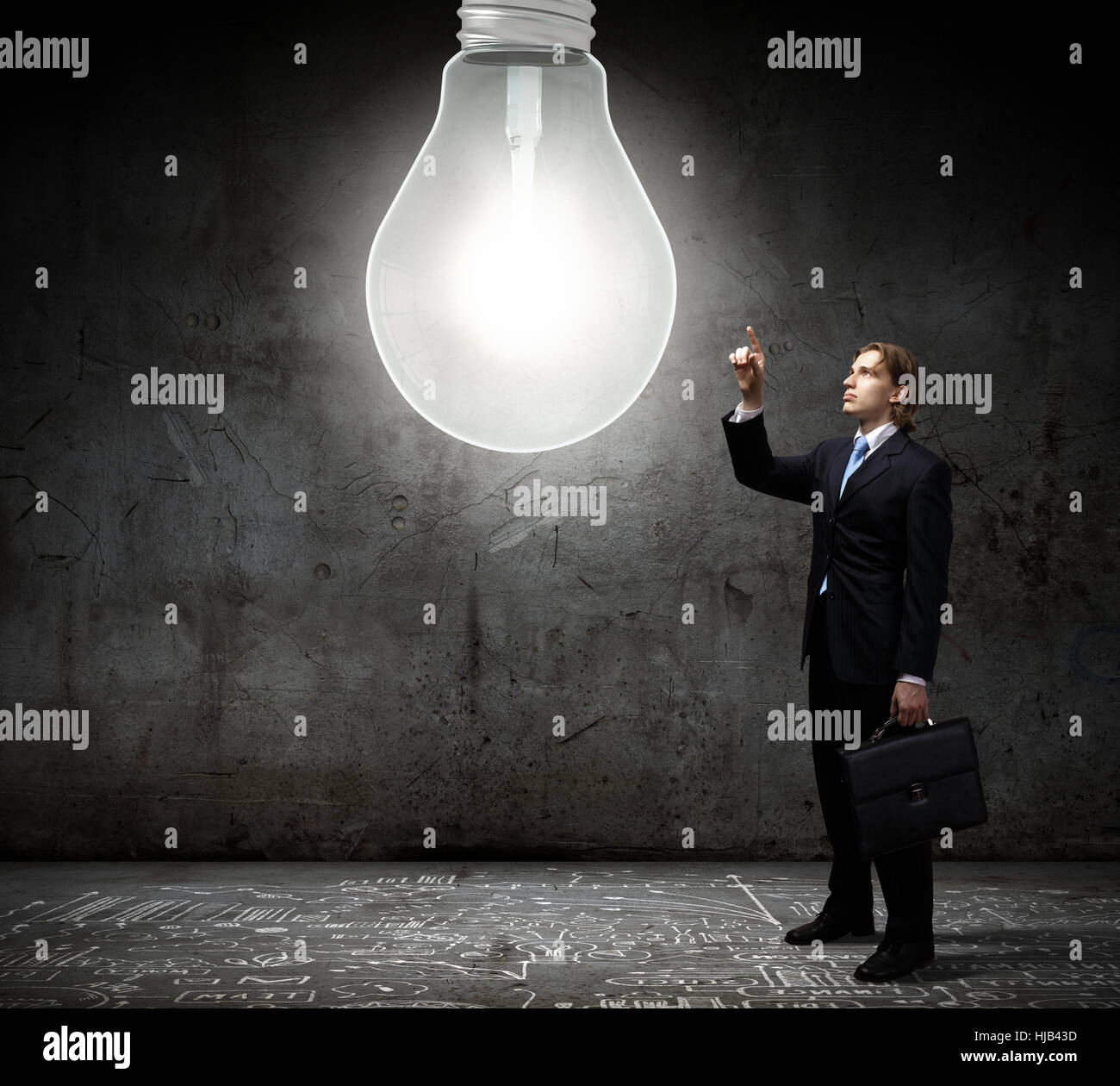 Young businessman and big light bulb against cement wall hi-res stock ...