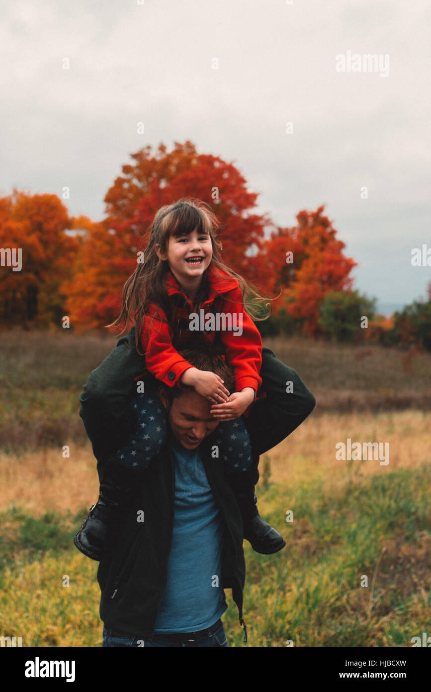 Mid adult man giving daughter a shoulder carry in field Stock Photo - Alamy