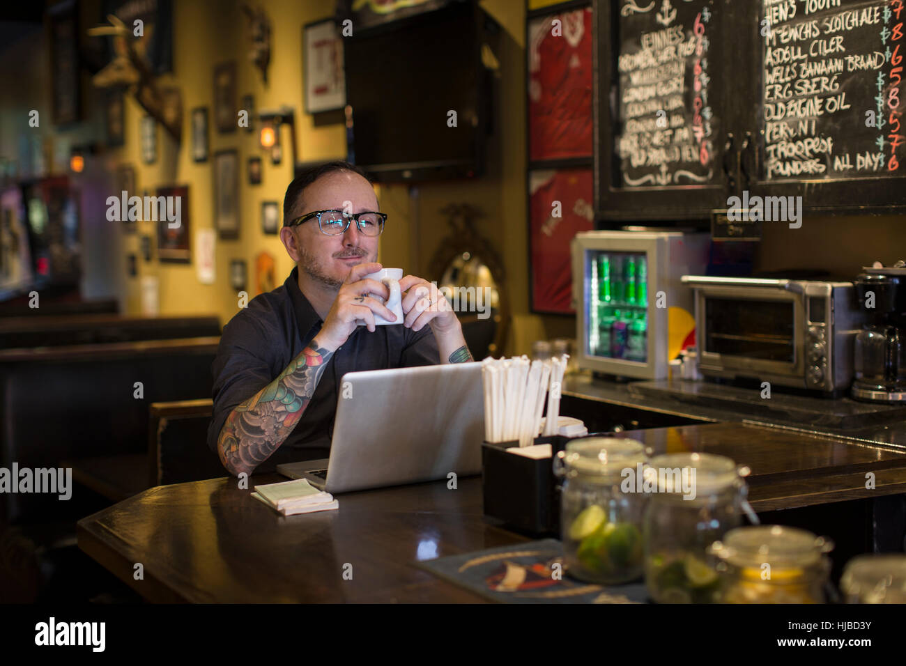 Barman having a coffee break at public house table Stock Photo - Alamy
