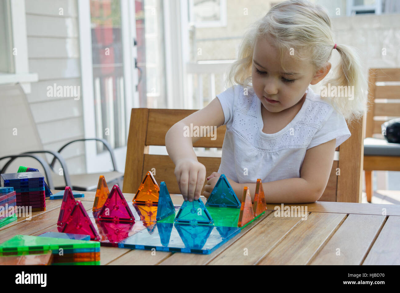 Young girl playing with triangular building shapes Stock Photo - Alamy