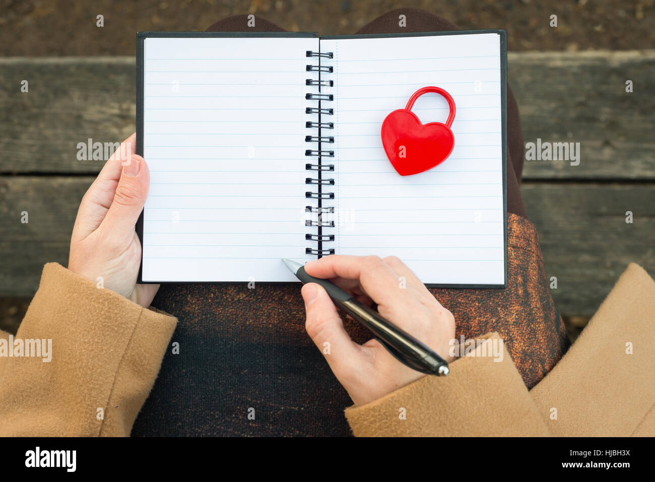 female hands holding notebook with closed red padlock in heart shape ...