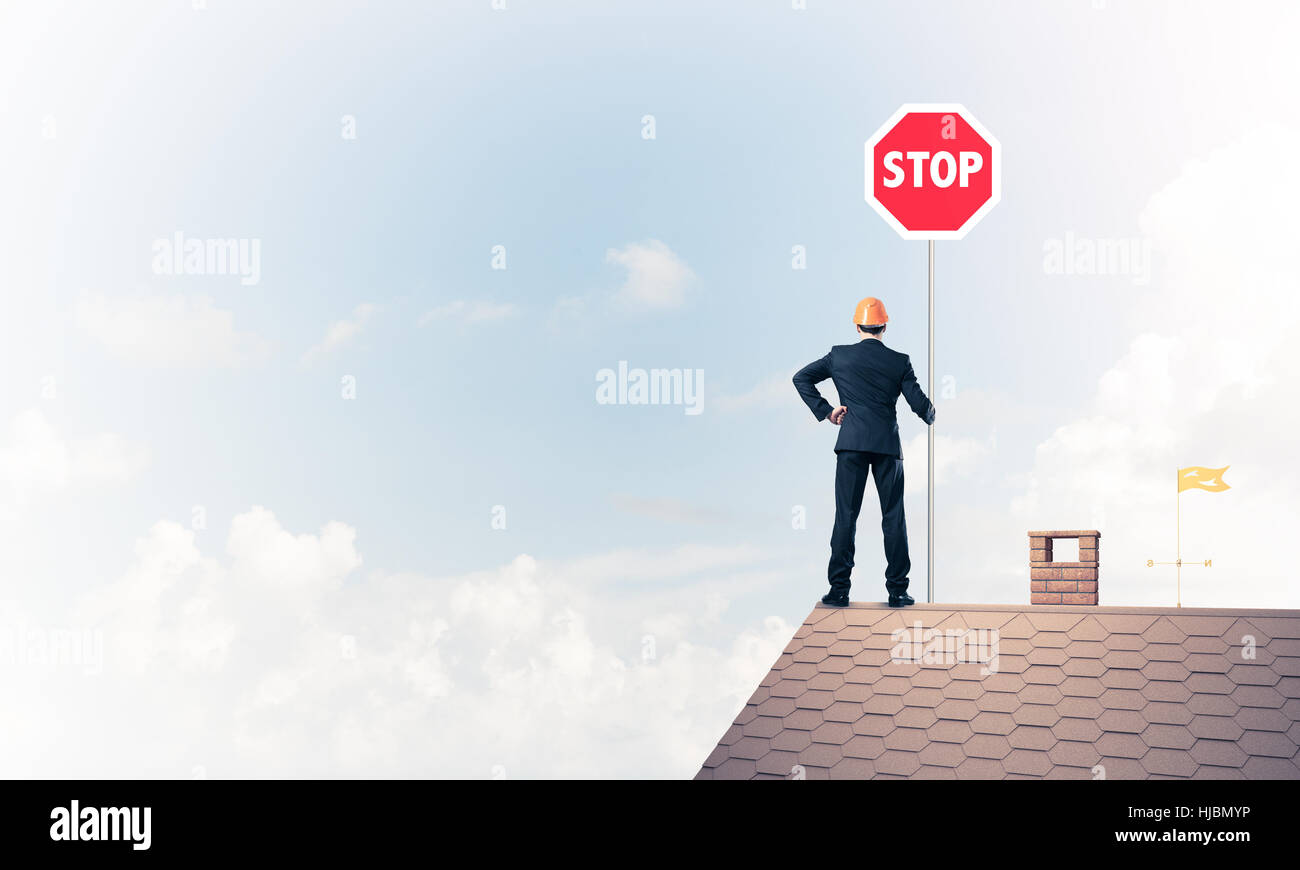 Caucasian businessman on brick house roof showing stop road sign Stock ...