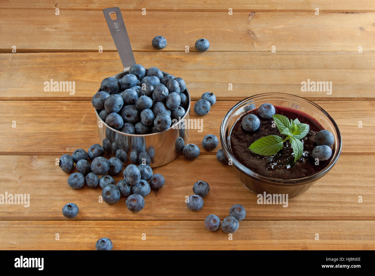 Blueberry jam in a glass bowl with scattered blueberries and a ...