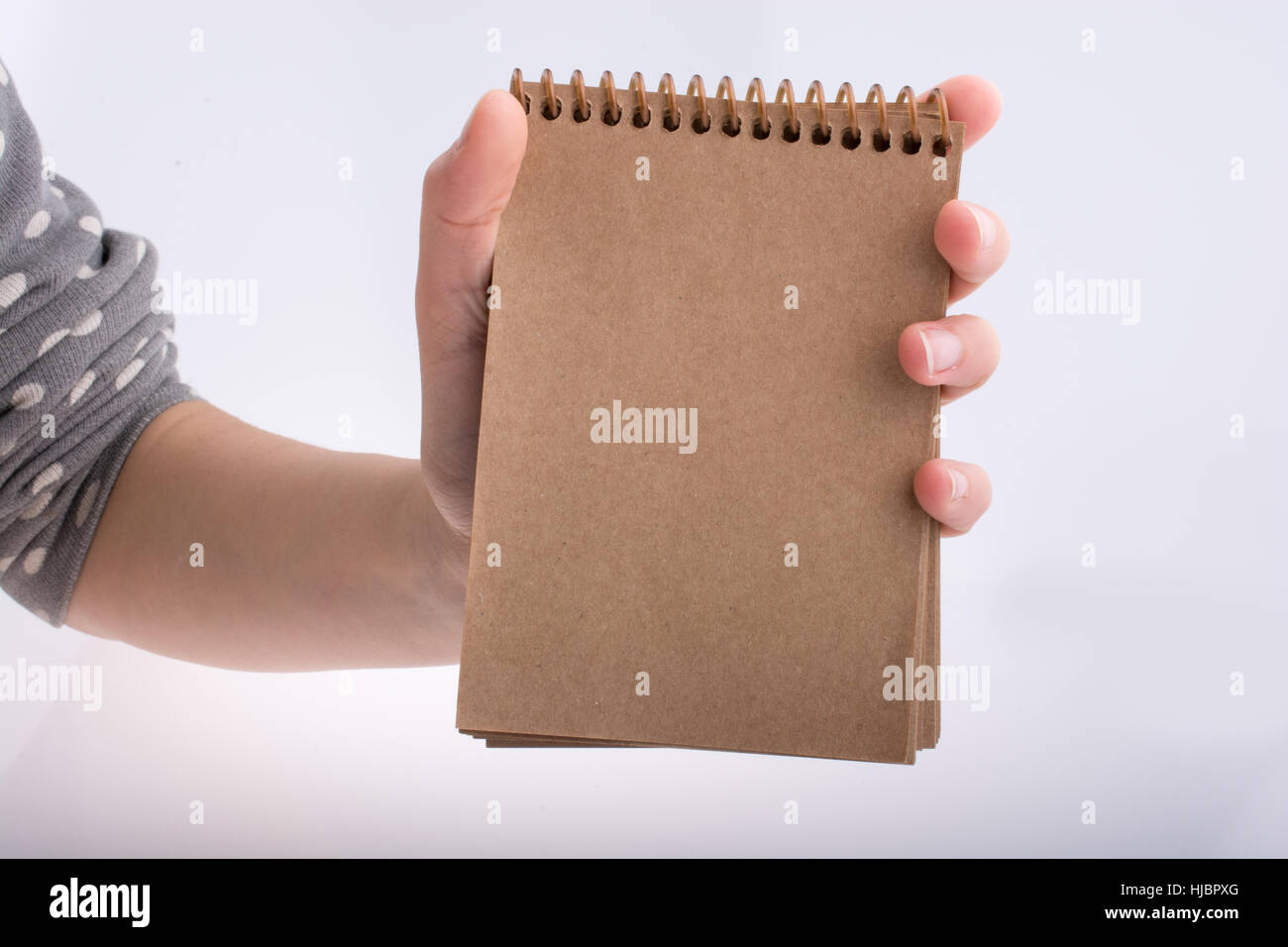Hand holding brown color notebook on a white background Stock Photo - Alamy