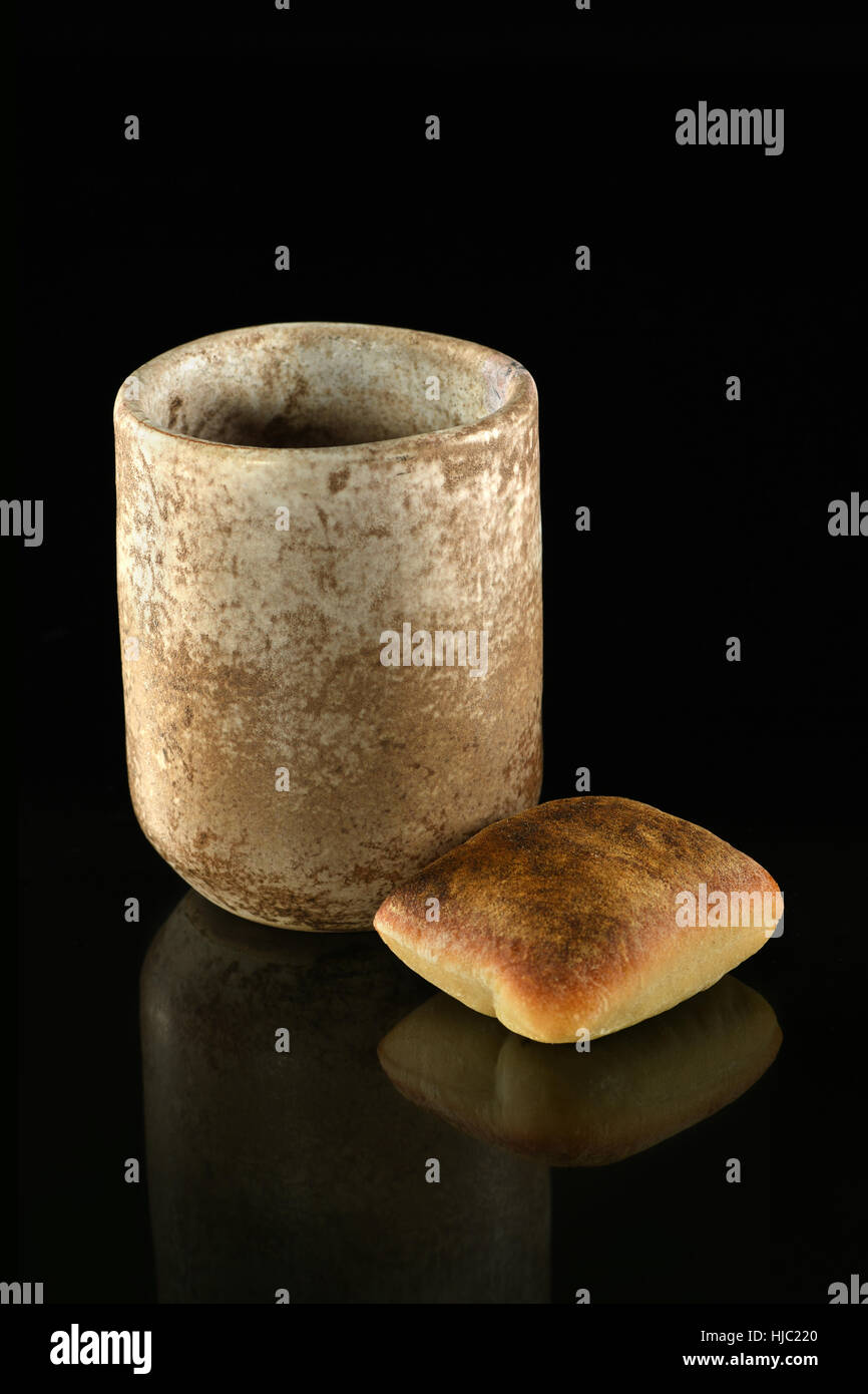 Cup of wine and bread as symbols of Communion over dark background ...