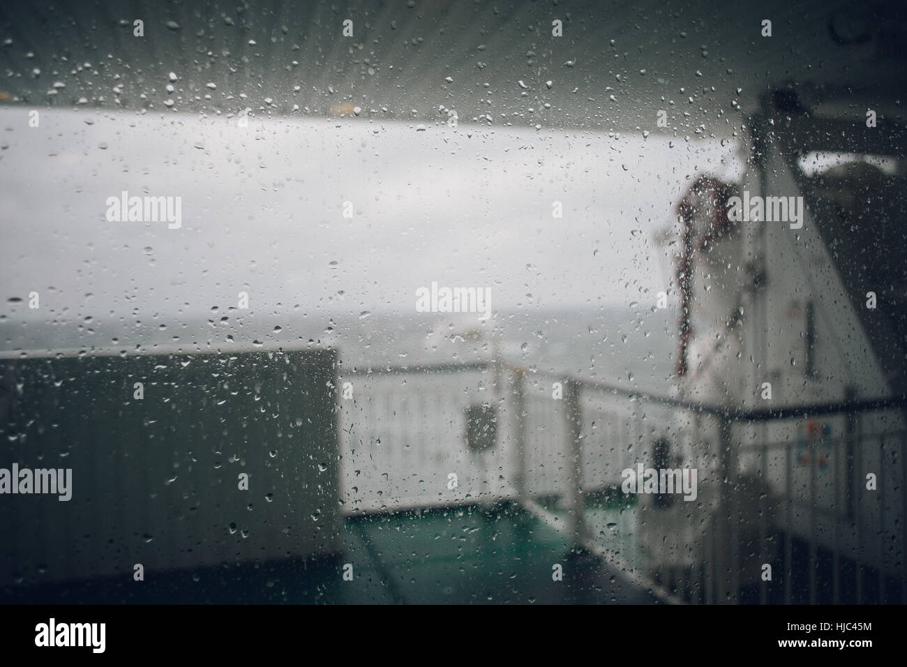Blurred image of ferry deck through window, stormy weather, drops on ...