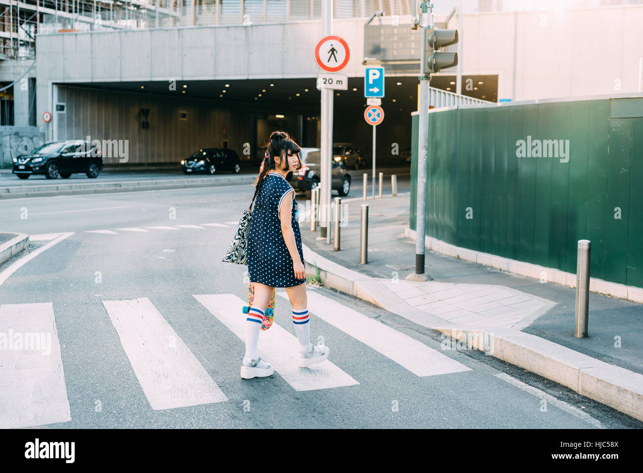 young beautiful asian millennial woman nonconformist skater walking outdoor in the city ...