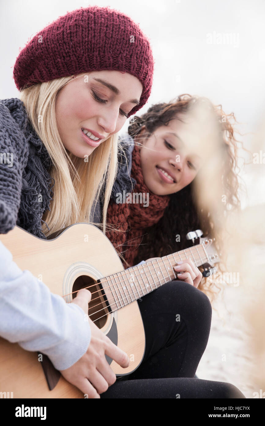Two young women playing guitar at beach, Western Cape, South Africa ...