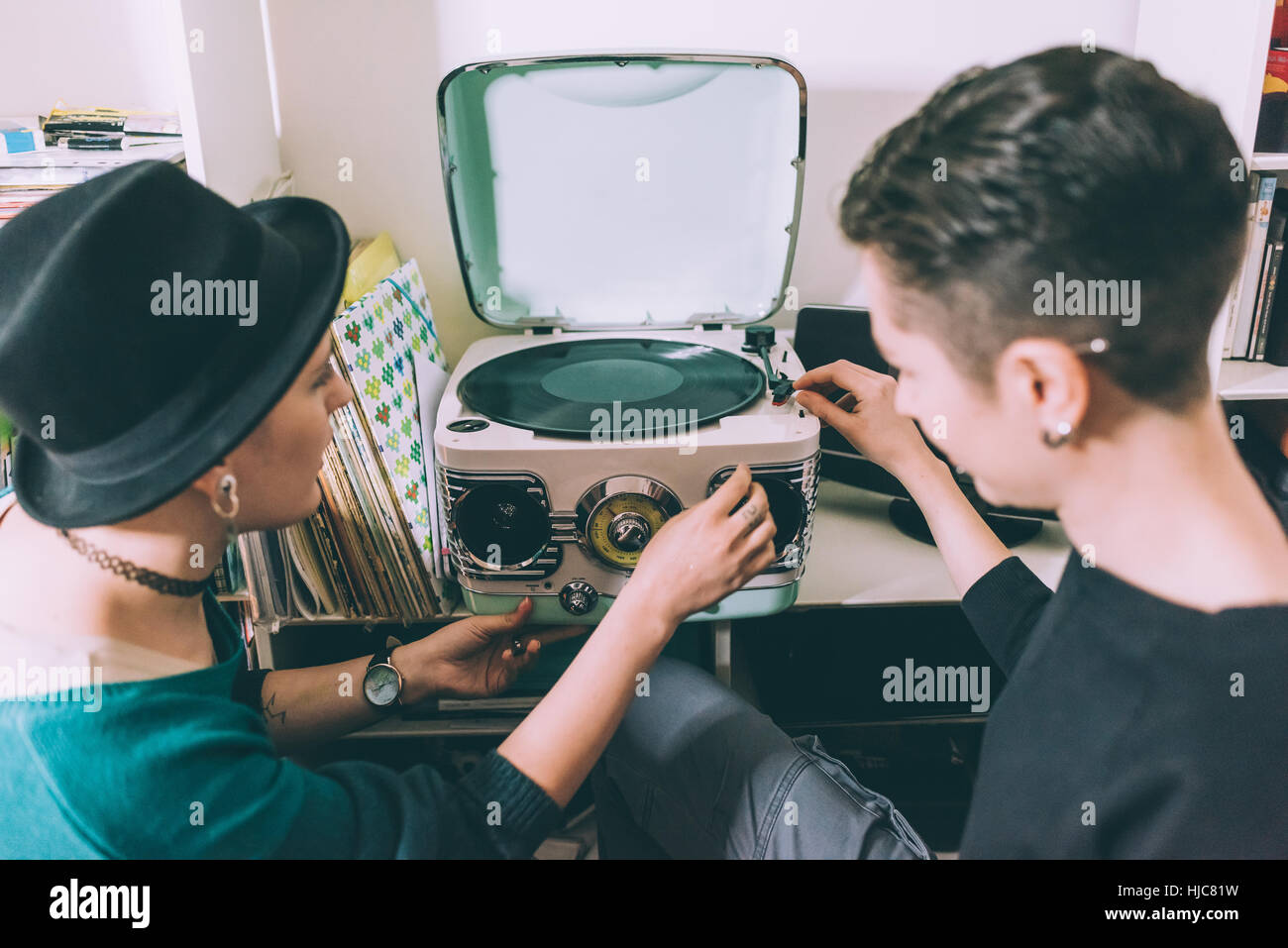 Over shoulder view of two young women playing vinyl on vintage ...