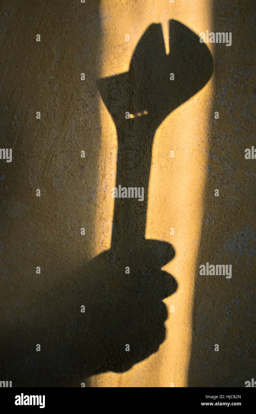 Hand holding spanner on the yellow and black grunge concrete background ...