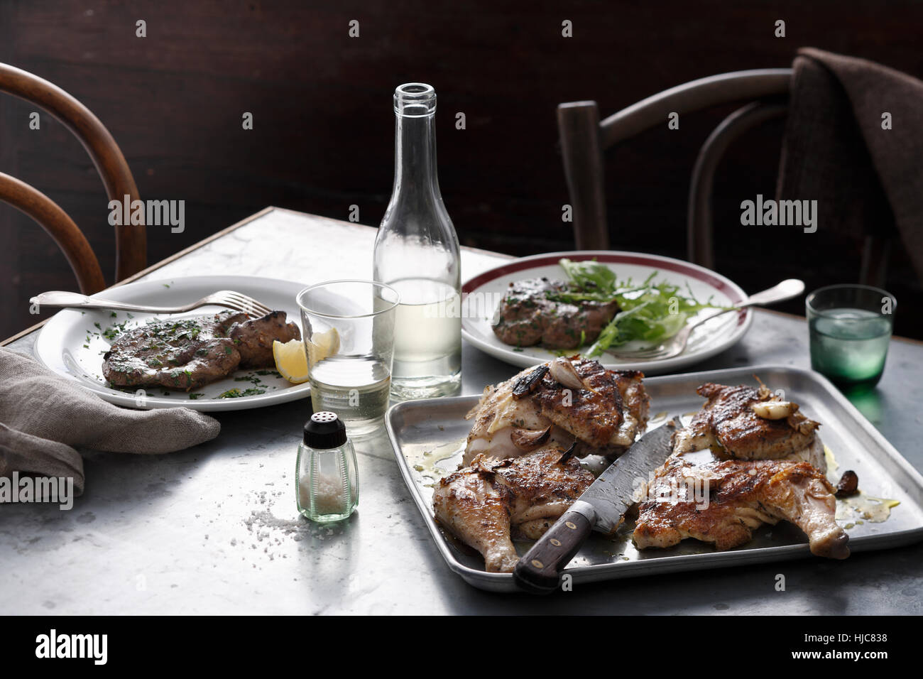 Bistro meal of roast spatchcock and calf liver with white wine on table ...