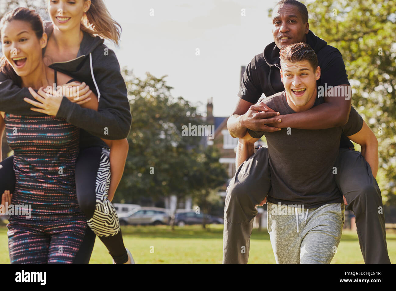 Men and women having fun training in park, having piggy back race Stock ...