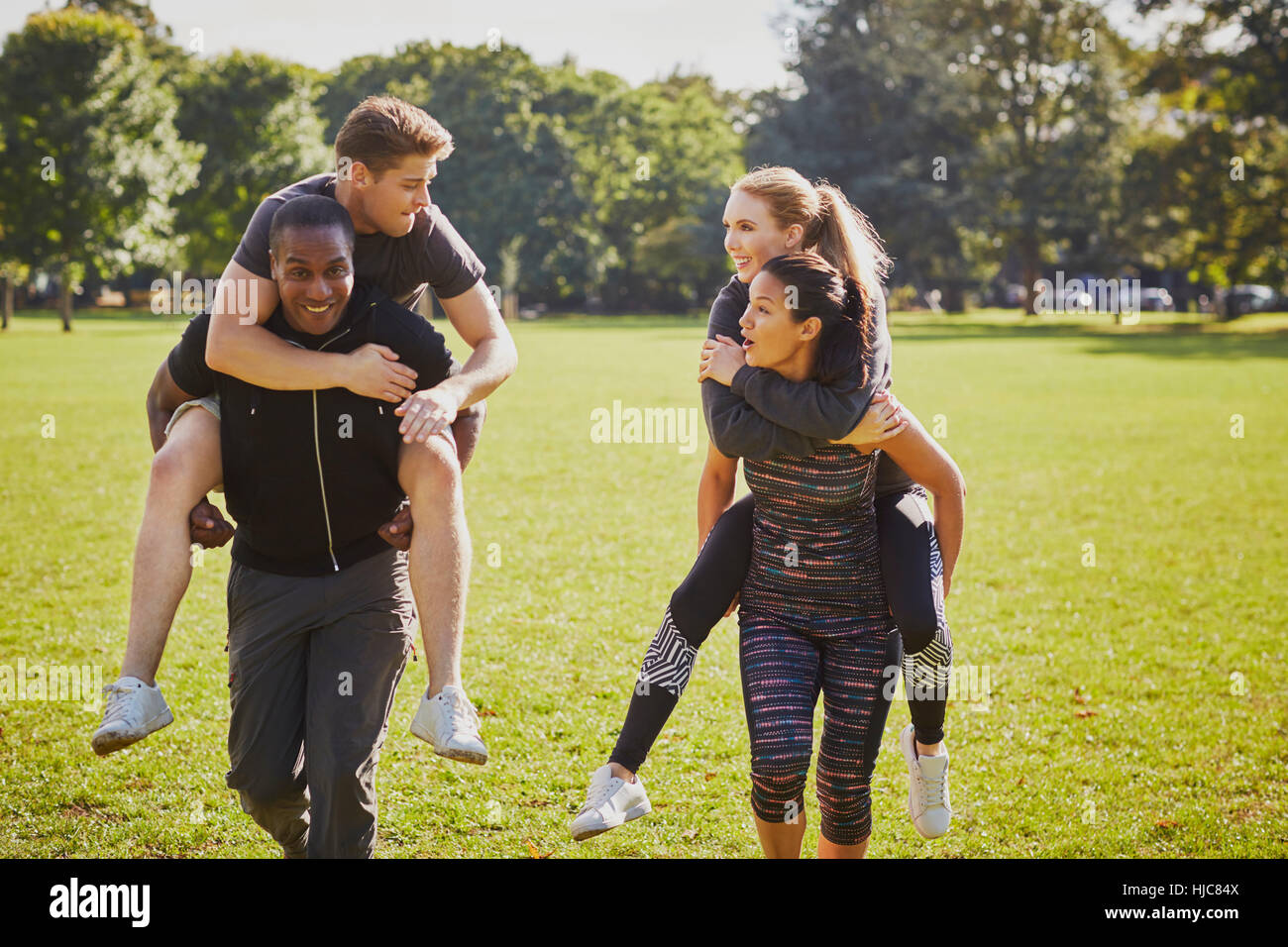 Men and women having fun training in park, having piggy back race Stock ...