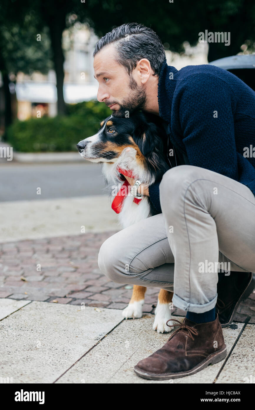 Mid adult man crouching with pet dog on city sidewalk Stock Photo - Alamy