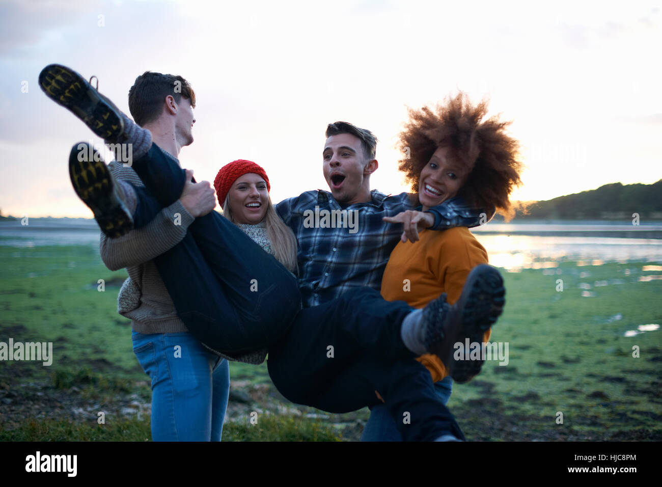Young man and woman carrying friends at seaside sunset Stock Photo - Alamy