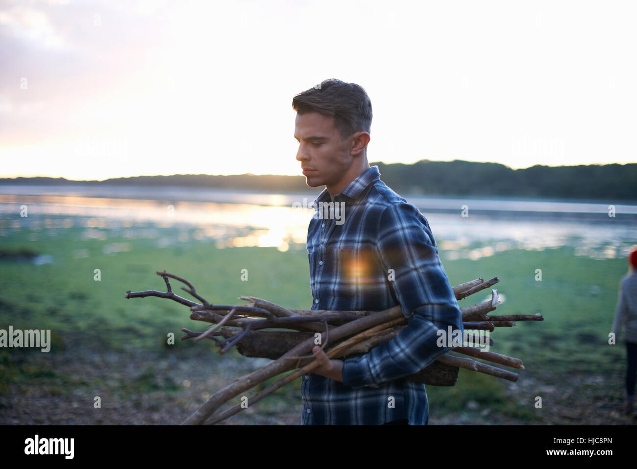 Young man carrying sea driftwood at sunset Stock Photo - Alamy