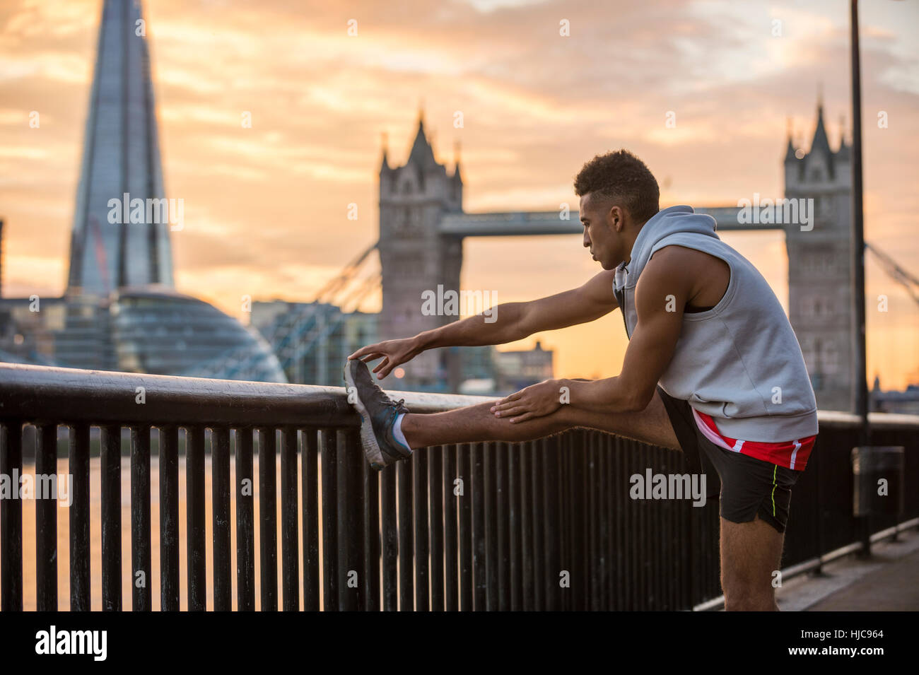 Man stretching against railing, Tower Bridge and The Shard in ...