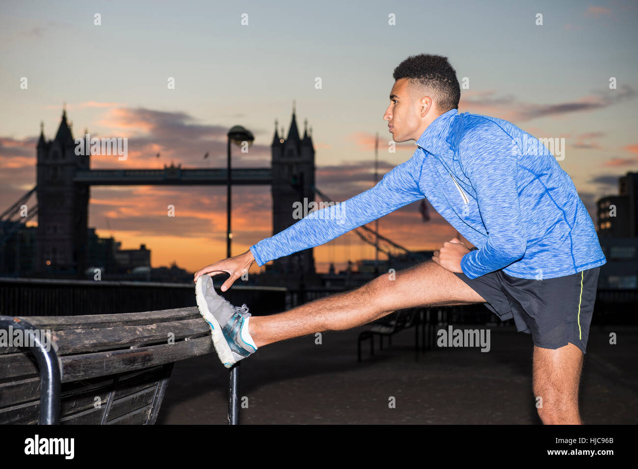 Man stretching by riverside, Tower Bridge in background, Wapping ...