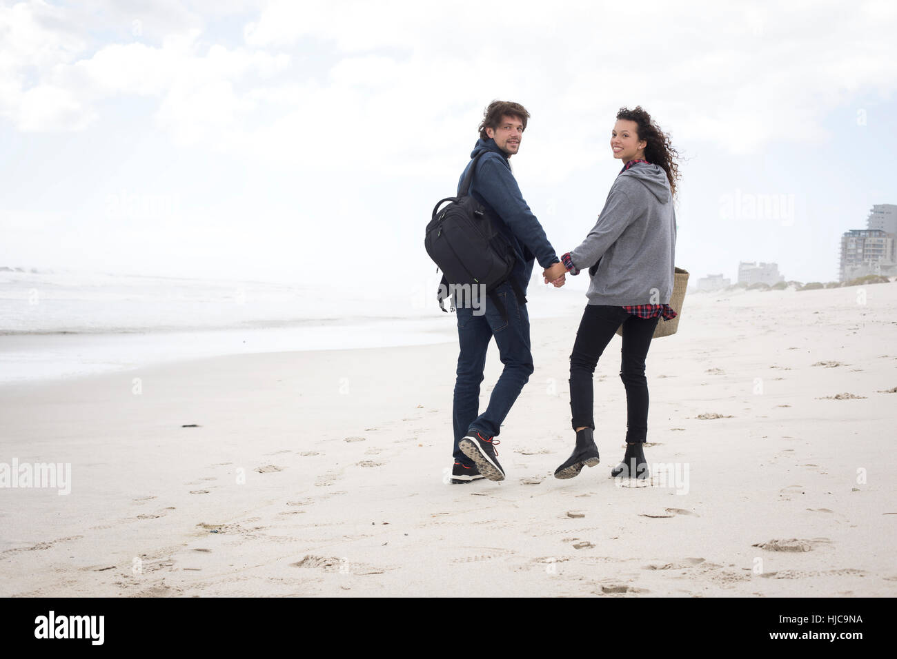 Rear view portrait of young couple strolling on beach, Western Cape ...