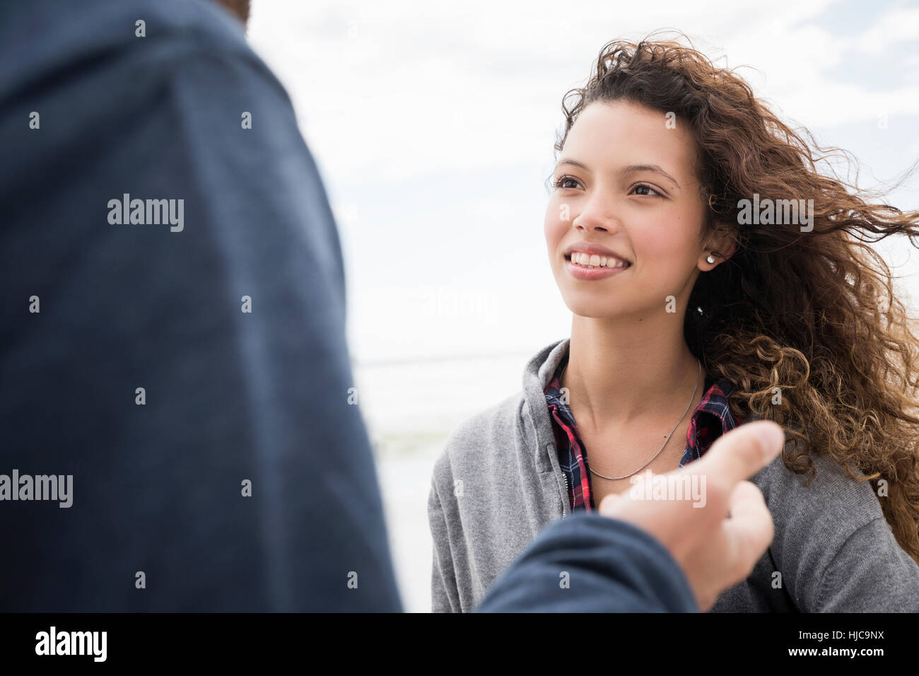 Over shoulder view of young couple talking on beach, Western Cape ...