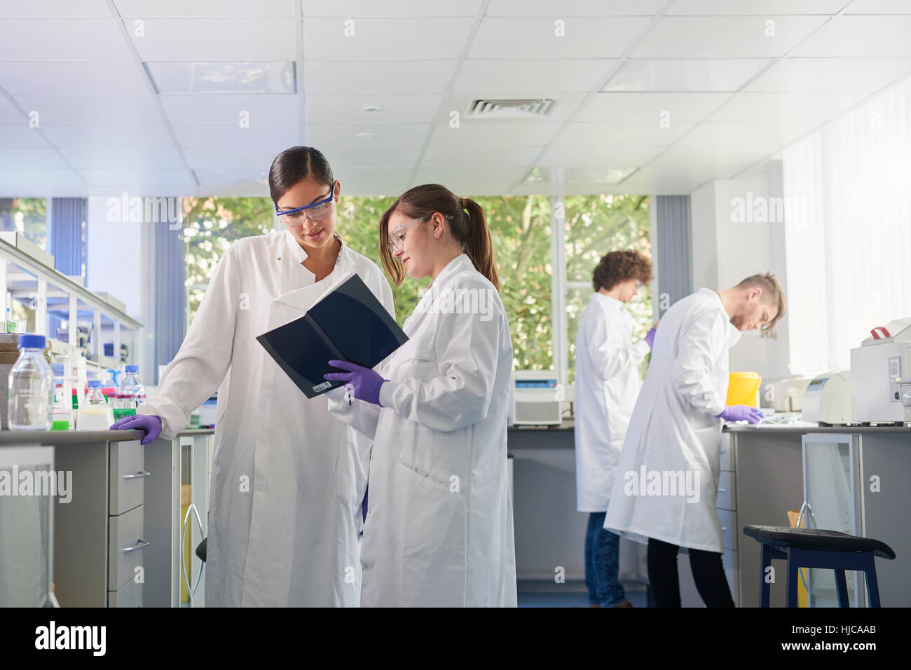 Scientists in laboratory discussing notebook Stock Photo - Alamy