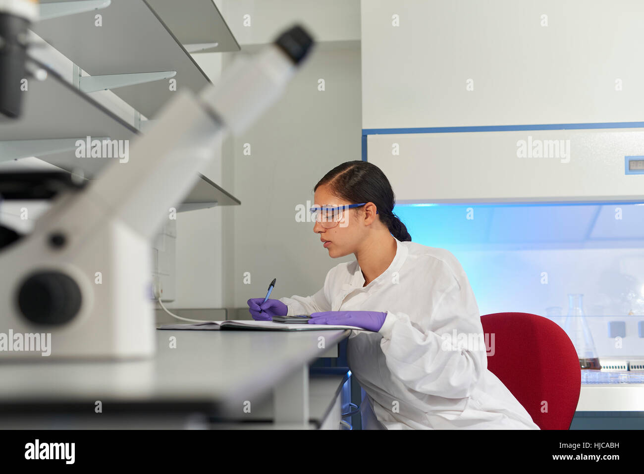 Scientists in laboratory writing in notebook Stock Photo - Alamy