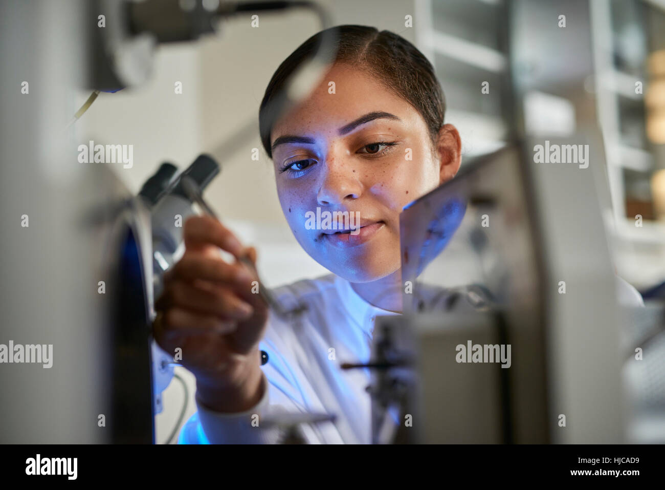 Scientists placing object on scientific equipment using tweezers Stock ...