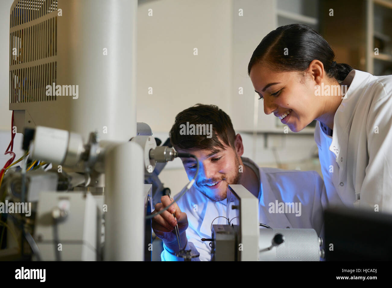 Scientists in laboratory using scientific equipment smiling Stock Photo ...