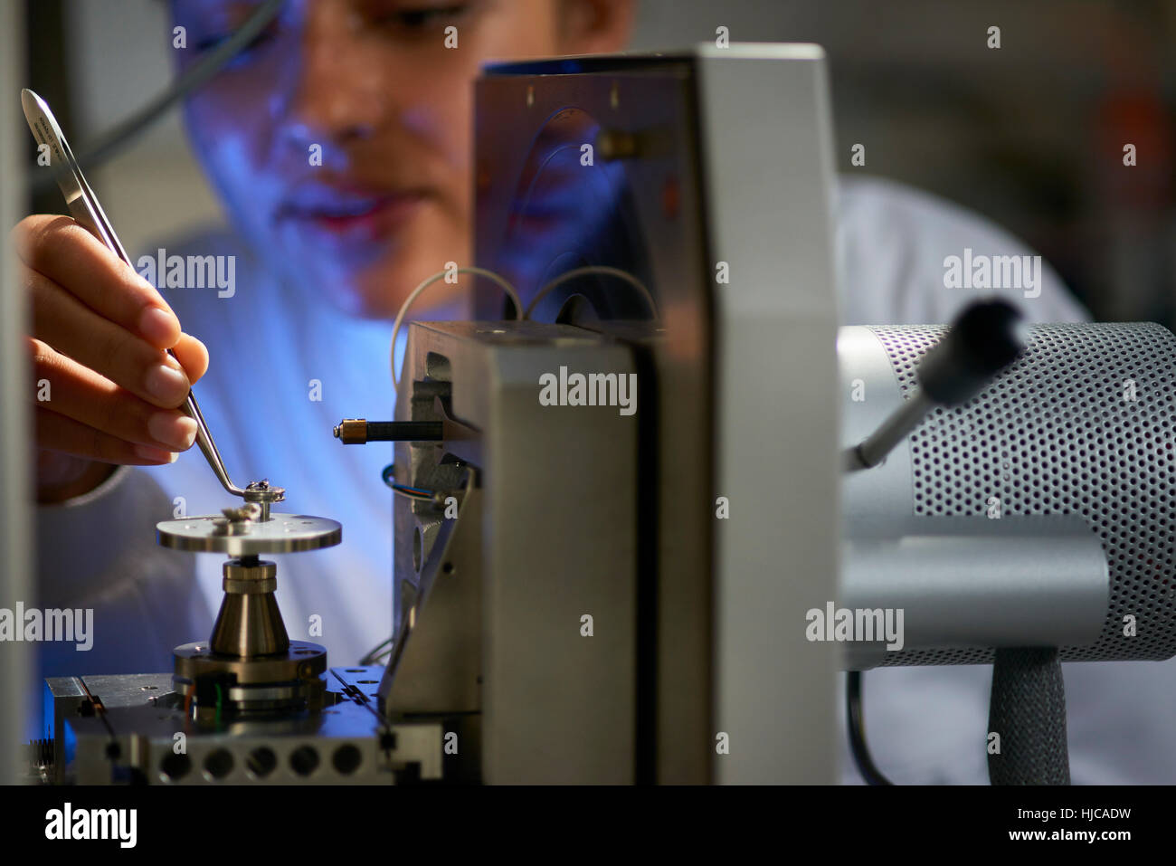 Scientists placing object on scientific equipment using tweezers Stock ...