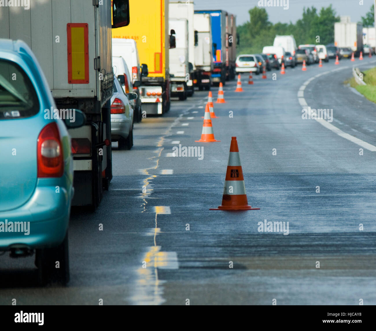 Rear view of rows of traffic queueing on highway with traffic cones ...