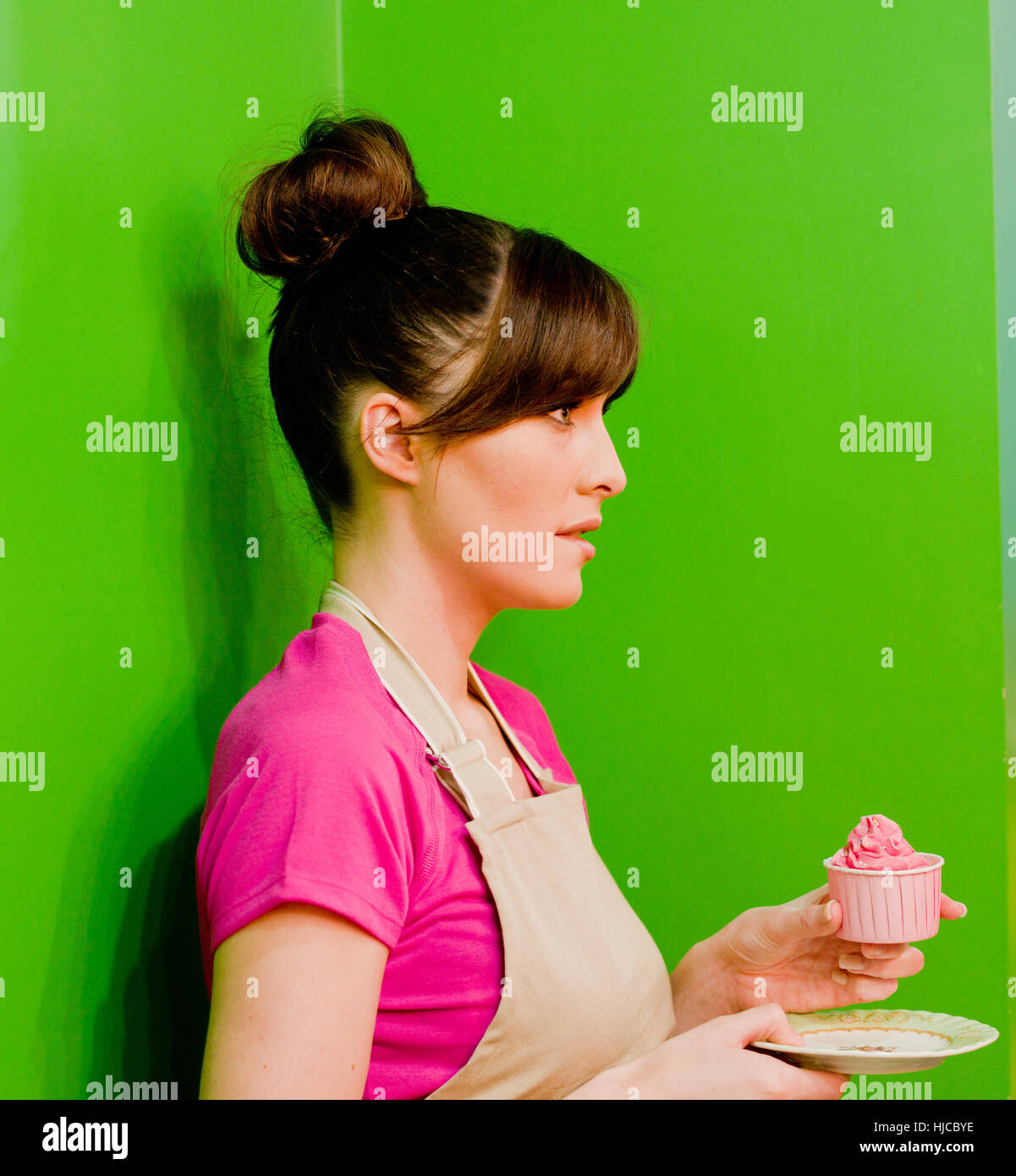 Young women Baker Holding cup cake feeling guilty about eating it Stock ...