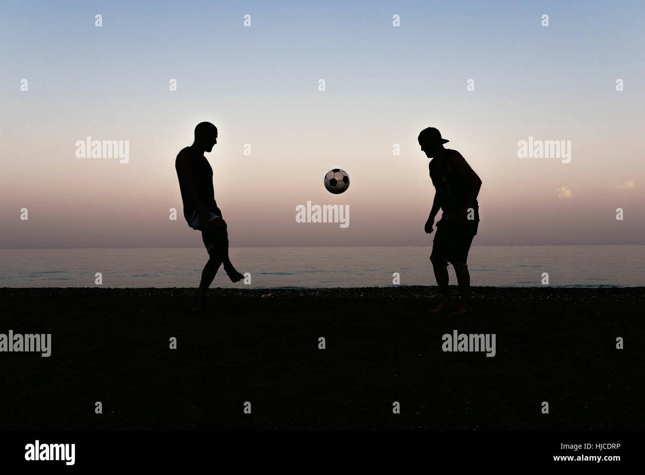 Two friends playing soccer in the beach Stock Photo - Alamy