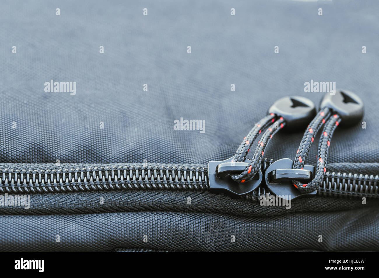 Close focus on two zippers with short striped nylon rope fastened on ...
