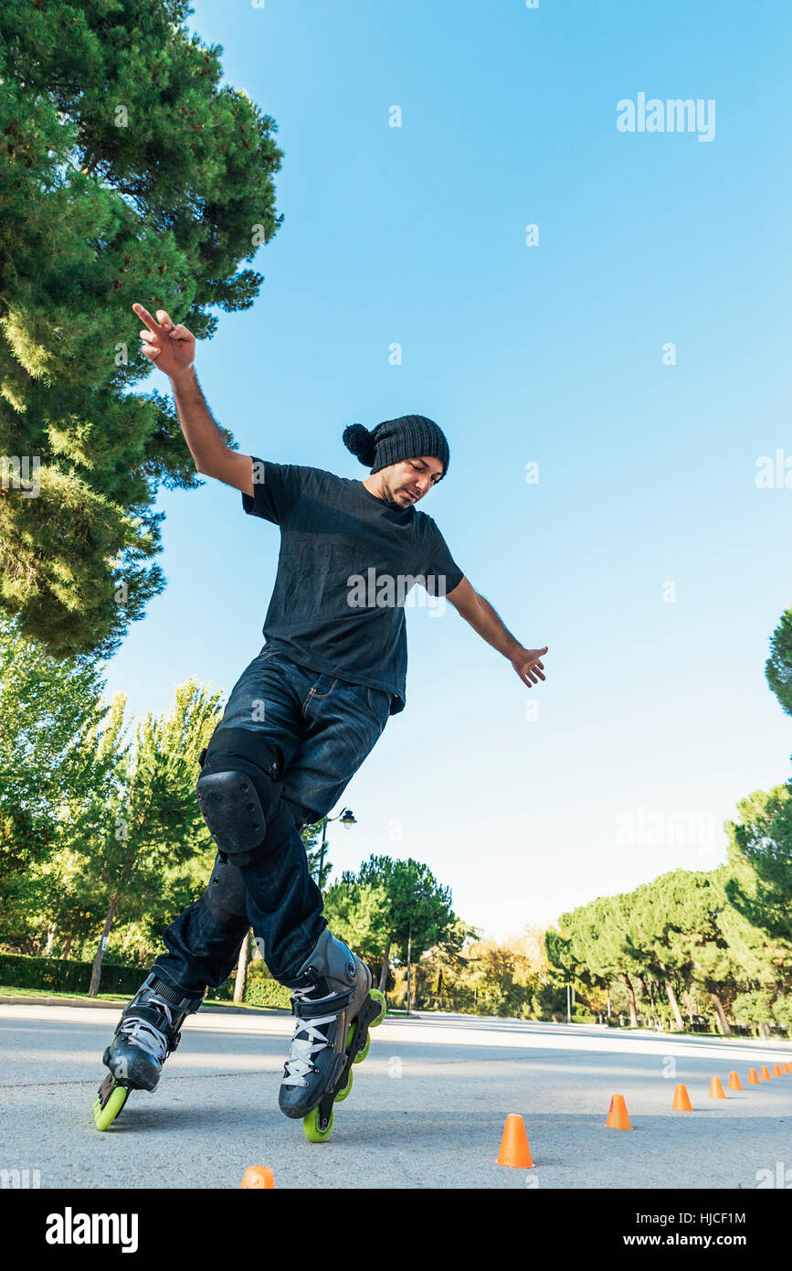 Urban young man on roller skates on the road at summer time. Roller ...