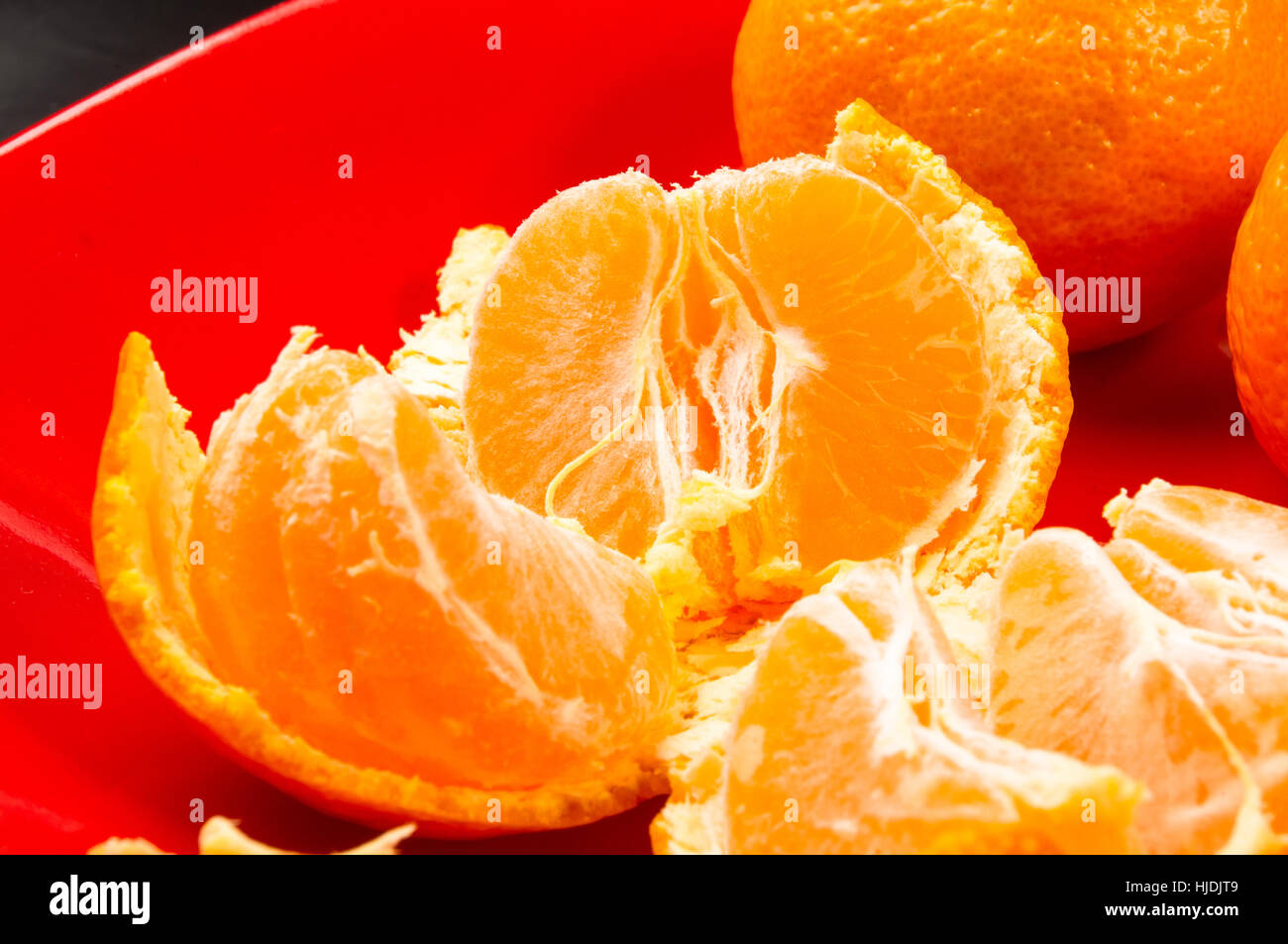 tangerines, peeled tangerine and tangerine slices in a red plate on ...