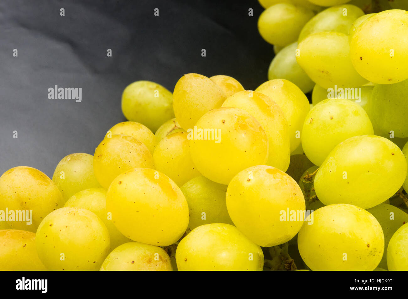 Large grapes cluster amber color on black background Stock Photo - Alamy