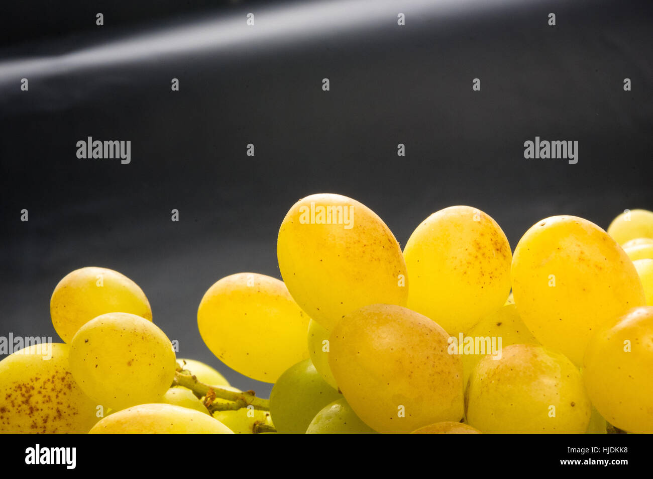 Large grapes cluster amber color on black background Stock Photo - Alamy