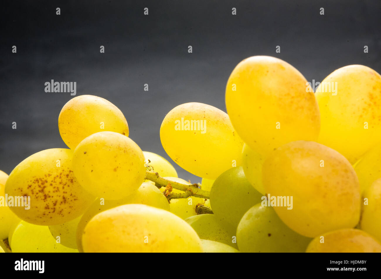 Large grapes cluster amber color on black background Stock Photo - Alamy