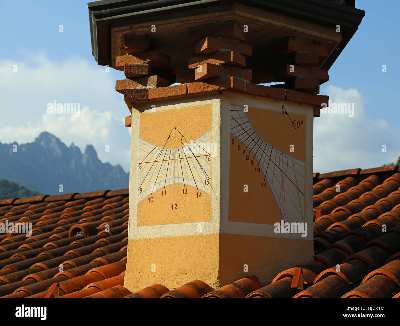 ancient sundial with hour numbers on the chimney of a house facing ...