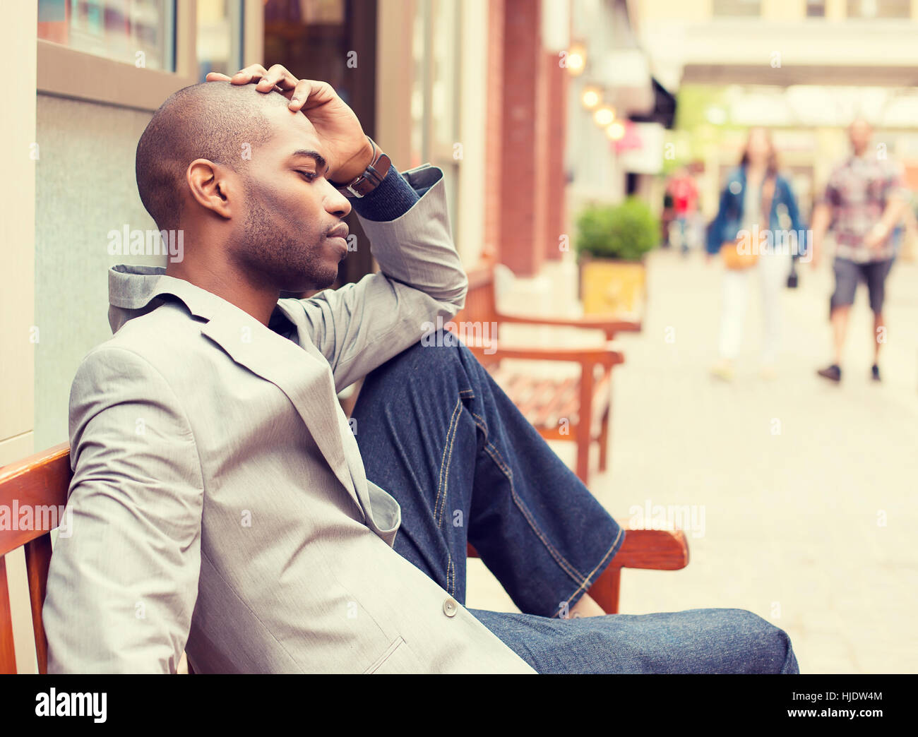 side profile stressed young casual businessman sitting outside ...