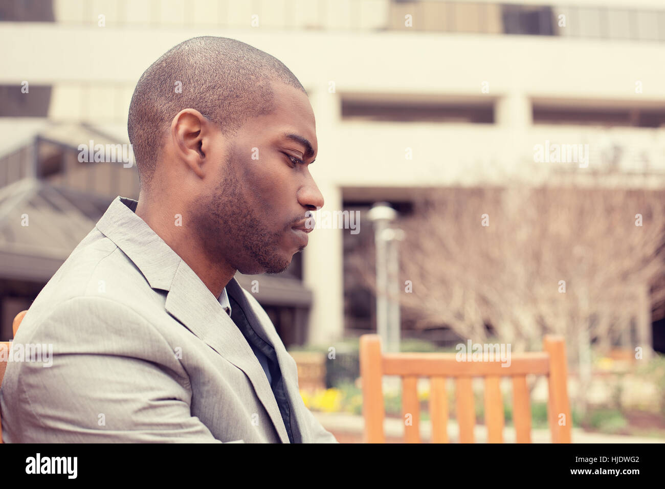 side profile portrait stressed young businessman sitting outside ...