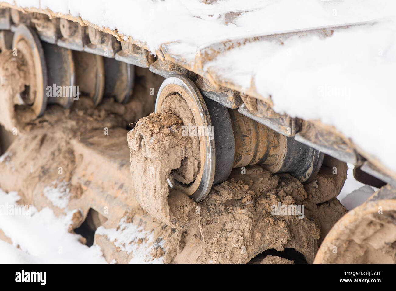 Detail of caterpillar track in construction site with dust and snow ...