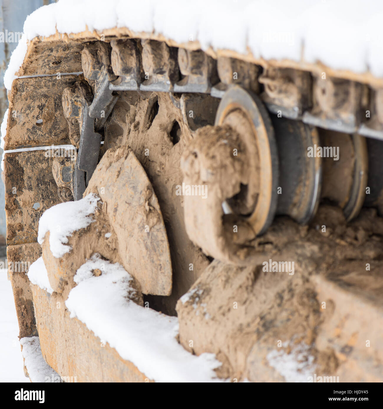 Detail of caterpillar track in construction site with dust and snow ...