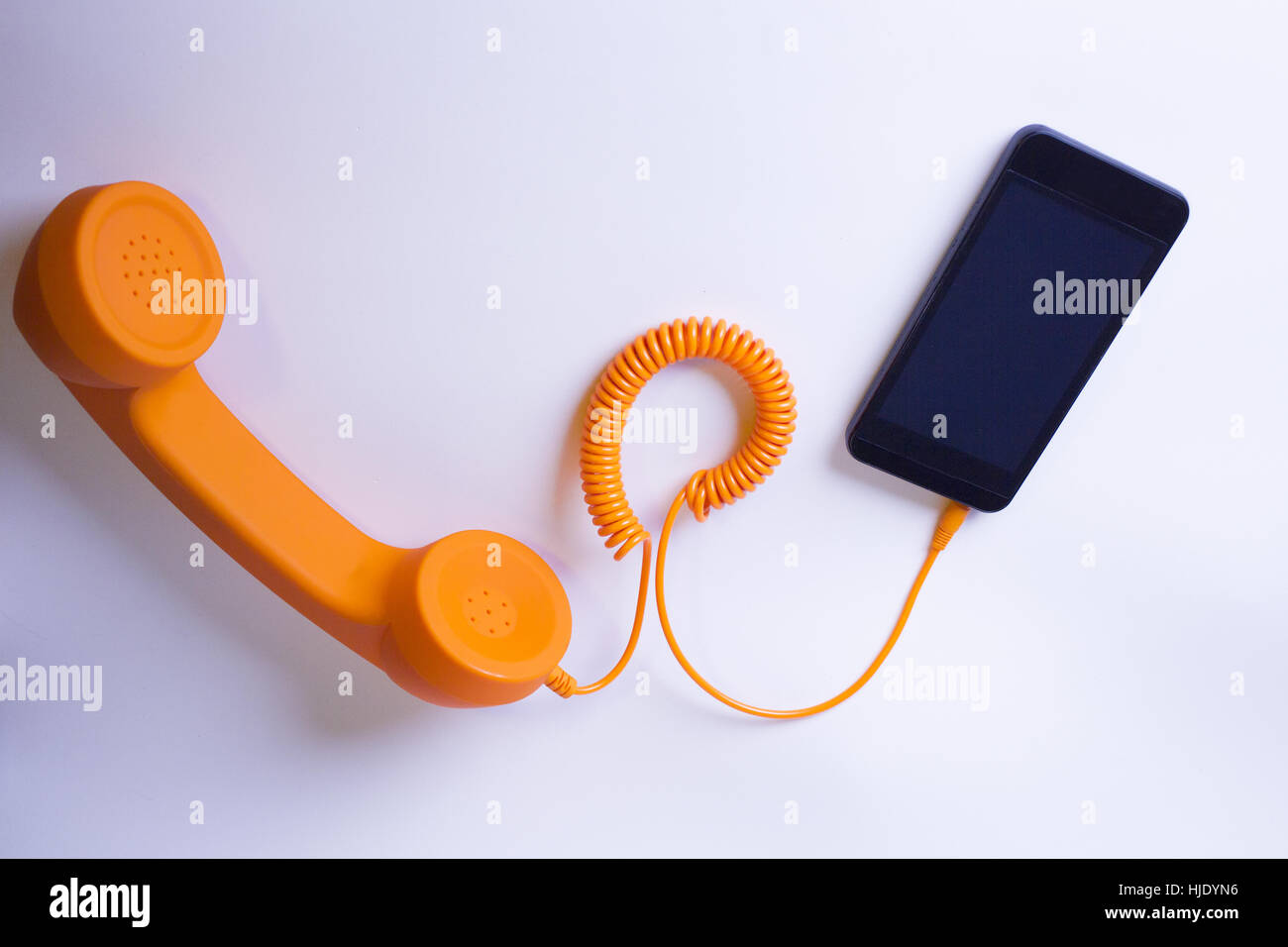 Orange analog phone and smartphone connected by a cable Stock Photo - Alamy