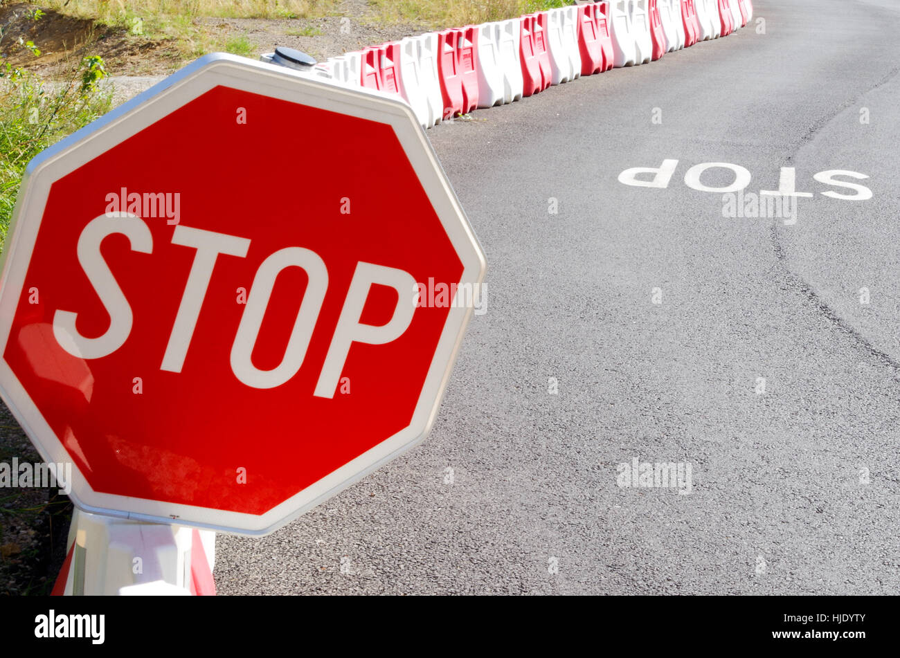 Red stop sign and STOP written on aslphalt at a junction under ...