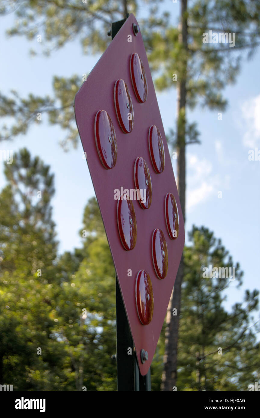 A red caution sign post against a forest and a bright blue sky Stock ...