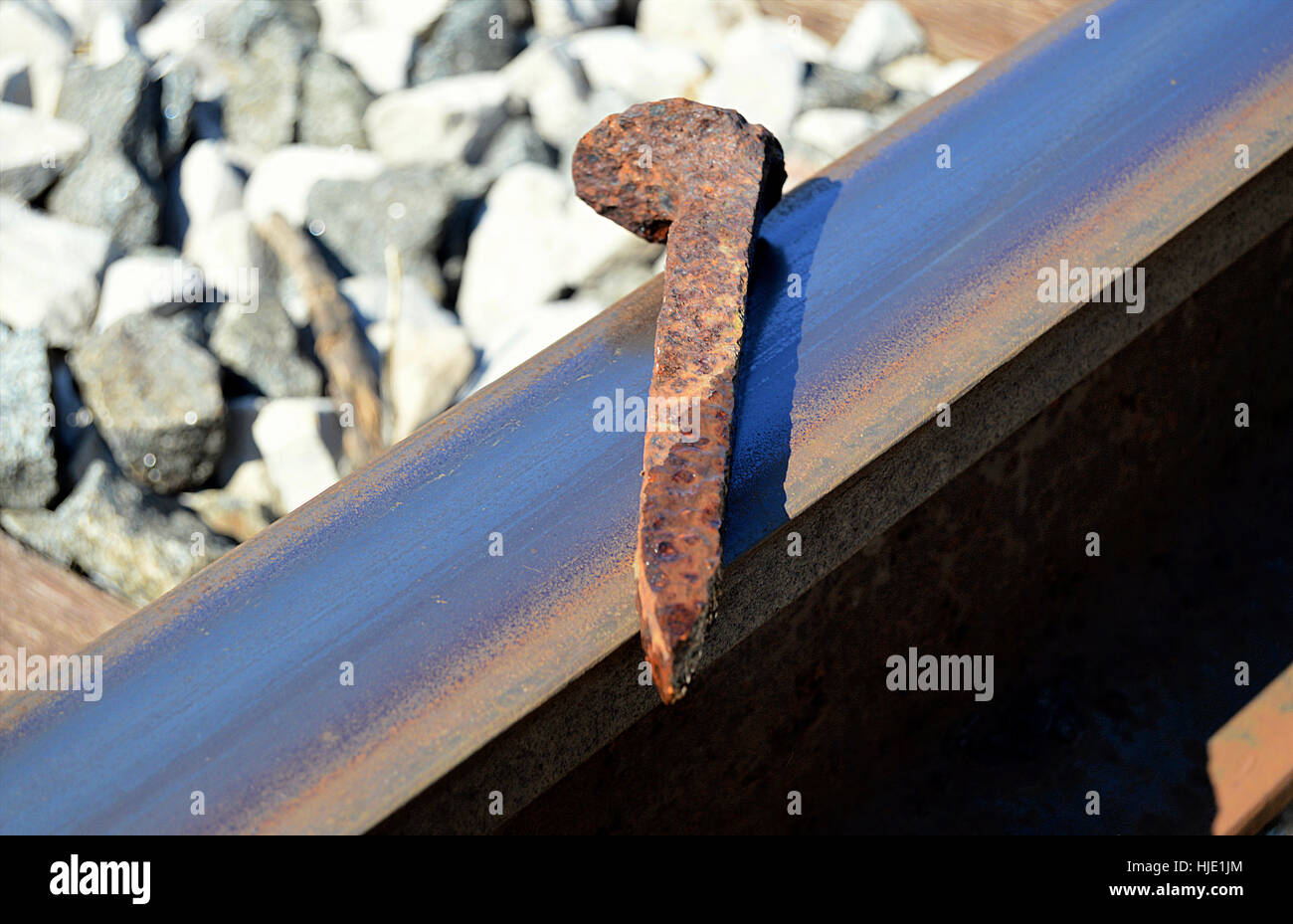 An iron railroad nail sitting on top of railroad track. Concept ...