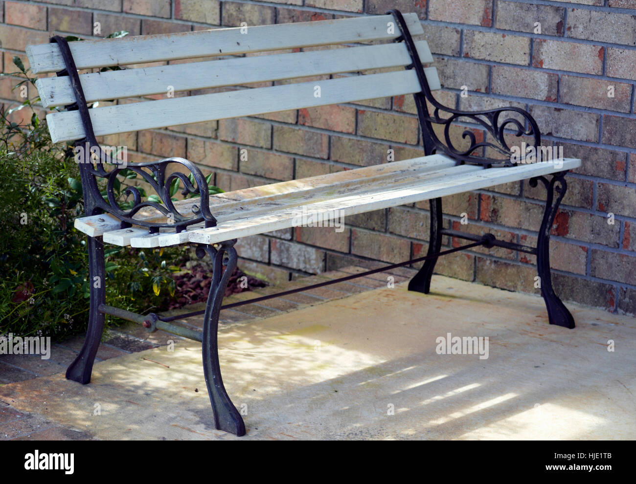 An old rustic bench sitting on a porch in front of a brick house Stock ...