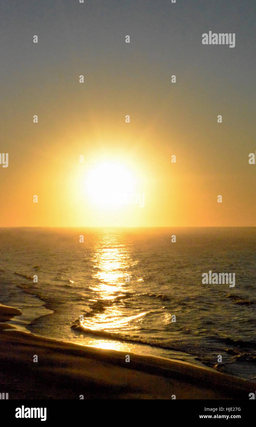 A glowing yellow sun rising over the ocean at Perdido Key, near ...