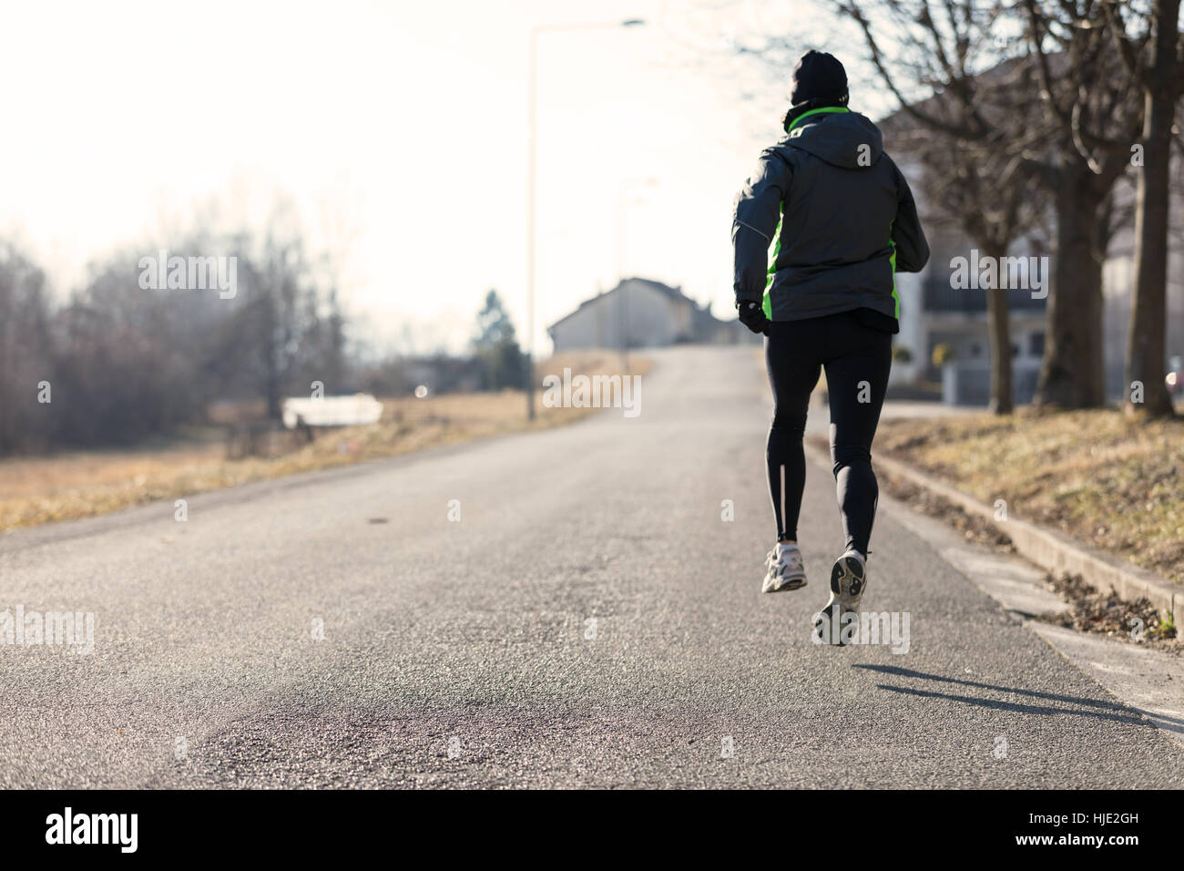 rear view of a woman running in the streets of a little town during ...